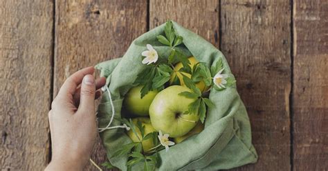 소박한 나무 테이블에 신선한 사과가 있는 에코 면 가방을 들고 있습니다 제로 폐기물 쇼핑 개념 플라스틱 금지 녹색 재사용 가능한 가방에 유기농 사과와 꽃 상위 뷰