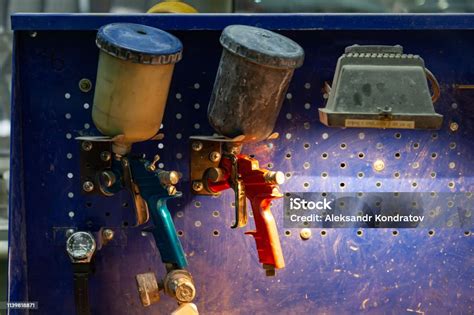 두 개의 바디 페인트 총 분무기 빨간색과 파란색 다른 도구와 조명 램프 옆에 차량 수리 워크샵에서 작업 대에 설치 자동차 서비스 업계 공장 산업 건물에 대한 스톡 사진 및