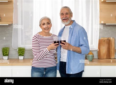 Smiling Elderly Spouses Holding Glasses With Wine While Posing In
