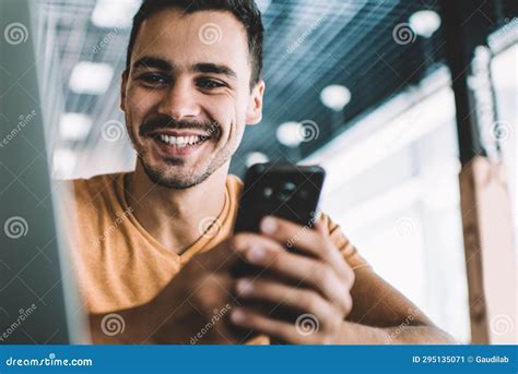 Satisfied Remote Worker Messaging On Phone Watching Laptop At Workplace
