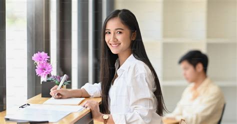 사무실에서 동료와 함께 나무 카운터 바에 앉아 문서 파일에 글을 쓰는 회계사로 일하는 젊은 아름다운 여성의 사진 사진 Unsplash의 태국 이미지