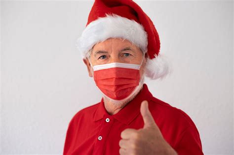코로나바이러스와 크리스마스 2020 엄지 손가락으로 수술 용 마스크를 착용 산타 모자와 노인의 초상화 흰색 배경에 적색 12월에 대한 스톡 사진 및 기타 이미지 Istock