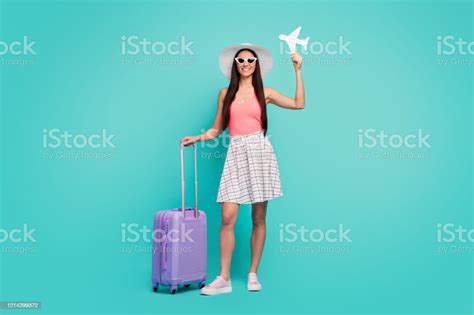 명랑한 여자 관광 홀드 백서 카드 비행기 의 전체 길이 사진 여름 주말 여행지 여행 가방 착용 선글라스 선글라스 운동화 고립 파스텔 청록색 배경 갈색 머리에 대한 스톡 사진