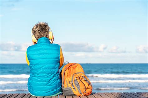 덥고 화창한 날 해변에서 노란색 여행 가방과 헤드폰을 착용한 파란색 재킷을 입은 여성이 관광 도시에 도착했습니다 여행 라이프