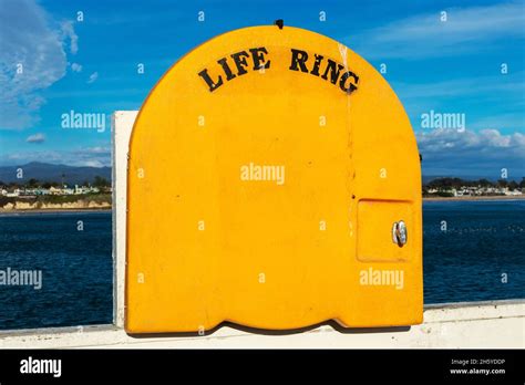 Life Ring Cabinet With Yellow Cover On Pier Railing Blurred Scenic