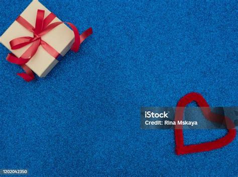 파란색 배경에 하나의 빨간 하트와 빨간색 리본 흰색 선물 상자 발렌타인 데이 개념입니다 발렌타인 인사말 카드입니다 복사 공간이 있는 플랫 레이 스타일입니다 0명에 대한 스톡