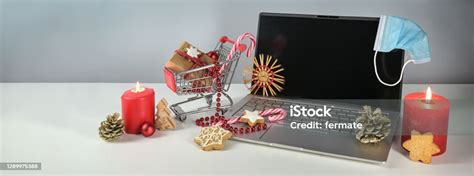 코로나바이러스 전염병 노트북 코비드19 전염병에 대한 수술 용 얼굴 마스크 불타는 촛불 크리스마스 장식 및 선물과 과자 회색 배경 복사 공간 파노라마 형식의 작은 쇼핑 카드