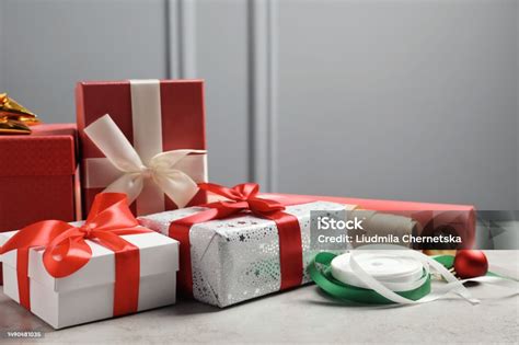 아름 다운 크리스마스 선물 상자는 종이에 싸여 있고 가벼운 테이블에 활로 장식 되어 있습니다 0명에 대한 스톡 사진 및 기타