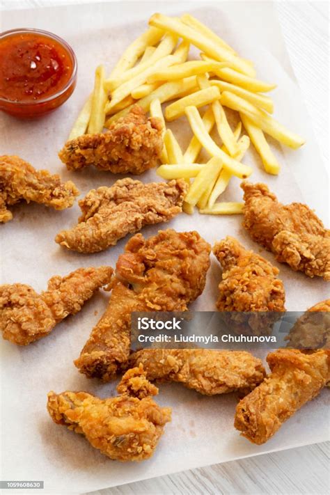 맛 있는 후 라 이드 치킨 나지만 매운 날개 감자 튀김 및 닭 손가락 흰색 나무 배경 근접 촬영 위에 베이킹 시트에 새 콤 달콤한 소스와 함께 가금류에 대한 스톡 사진 및
