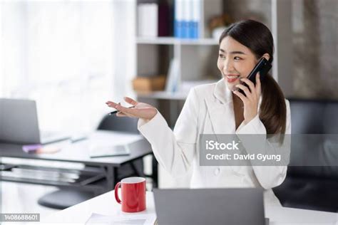 스마트 폰으로 이야기하고 사무실에서 일하는 사업가 그의 직장에 앉아있는 아시아 여성 비즈니스 아시아인에 대한 스톡 사진 및 기타 이미지 Istock
