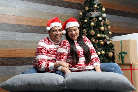 Adult Latino Man And Woman Couple Have Christmas Presents Lying On The Bed By The Tree With