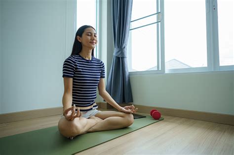 젊은 아시아 여성은 집에서 연꽃 자세로 명상하고 피트니스 복장을 입고 바닥에 앉고 휴식 평화 마음 챙김을 얻기 위해 호흡 운동을 합니다 25 29세에 대한 스톡 사진 및