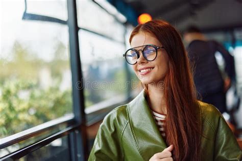 Woman Hipster With Red Hair And Glasses Sitting In Town In A Cafe At