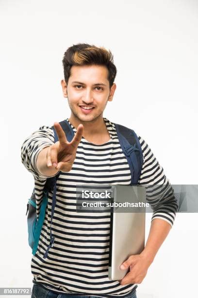 잘 생기고 젊은 인도 남성 대학생 대학도 서 노트북 이나 스마트 폰 잡고 흰색 바탕에 가방을 들고 가방에 대한 스톡 사진 및 기타 이미지 Istock
