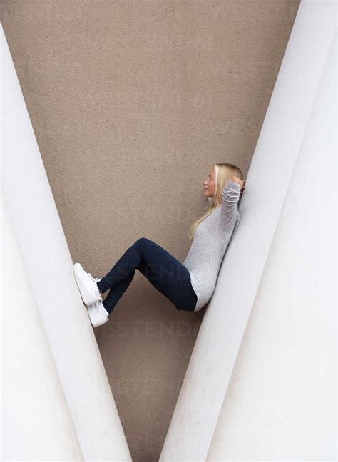 Blond Female Teenager Relaxing Between Concrete Columns Stock Photo