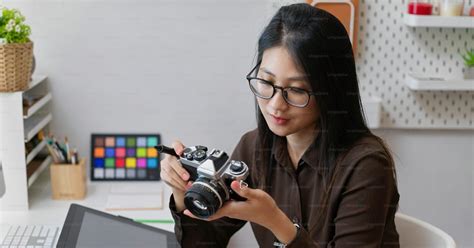 디자이너 용품이 있는 사무실 책상에 앉아 카메라를 가지고 일하는 여성 디자이너의 초상화 사진 Unsplash의 컴퓨터 이미지