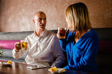 아침이나 오후에 카페 나 레스토랑에서 차 한 잔을 마시는 여성과 남성 여성과 남성 부부는 파란색과 흰색 셔츠를 입고 대화