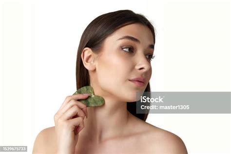 하얀 스튜디오 배경에 미용 마사지 도구로 얼굴을 돌보고 있는 건강한 피부를 가진 아름다운 젊은 여성 20 24세에 대한 스톡 사진 및 기타 이미지 Istock