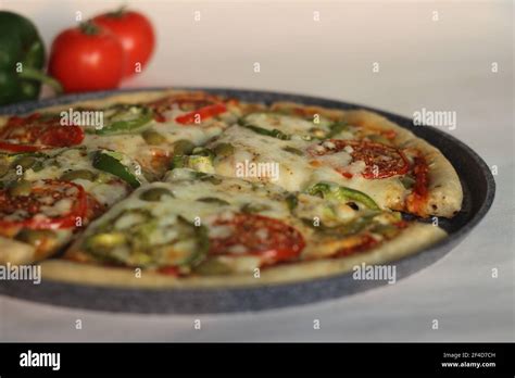 Home Baked Veg Pizza With Cheese Tomato And Bell Peppers Shot On White