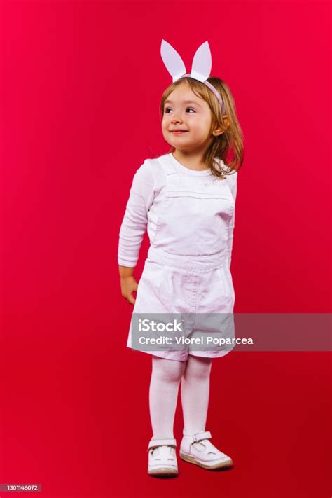 흰색 정장과 빨간 배경에 부활절 토끼 귀와 작은 미취학 소녀의 전체 길이 사진 광고에 대한 스톡 사진 및 기타 이미지 광고