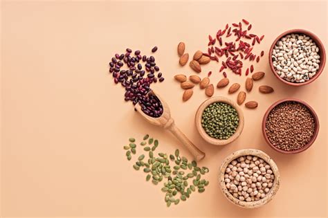 파스텔 핑크 배경에 건강한 채식주의 자 및 채식 슈퍼 푸드 콩 호박 씨앗 병아리 콩 메밀 녹두 아몬드와 고지 베리 상단보기 평평한 평신도 복사 공간 씨앗에 대한 스톡 사진