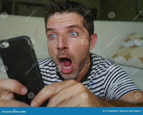 Young Perplexed And Shocked Man Using Mobile Phone Looking Internet
