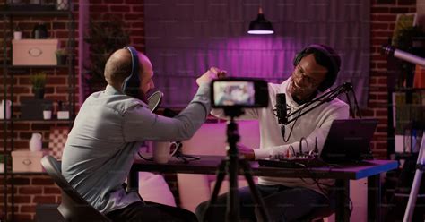 인터넷 라디오 호스트가 홈 스튜디오에서 게스트를 맞이하는 디지털 비디오 카메라를 사용하여 팟캐스트를 녹음하는 정적 삼각대 샷