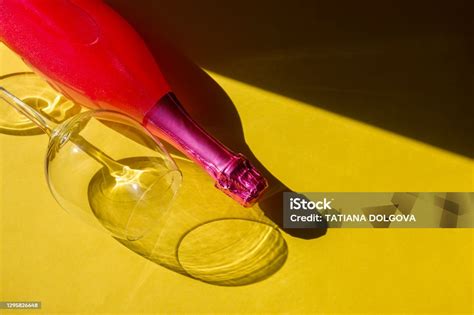 축제 파티 개념 노란색 배경에 분홍색 샴페인 유리와 병 햇빛은 유리와 병 그림자의 단단한 형태를 보여줍니다 하드 라이트 하드 섀도우 플랫 레이 3월에 대한 스톡 사진 및