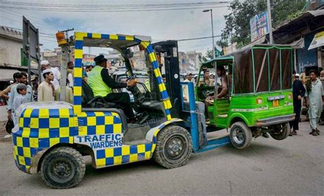 A Traffic Police Warden Is Picking Up A Wrongly Parked Rickshaw With The Help Of A Forklifter At