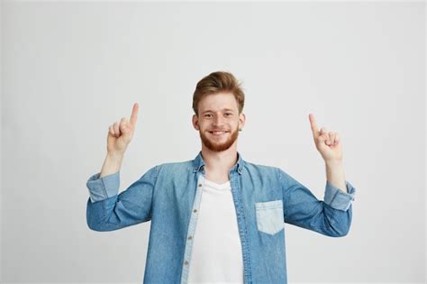 Free Photo Portrait Of Cheerful Young Man Smiling Pointing Finger Up