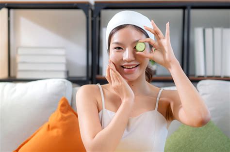 초상화 아름다움 젊은 아시아 여성은 스파에서 오이를 들고 얼굴에 주름과 회춘 피부를 위한 크림을 바르고 오이 초본 크림으로 건강을 위한 행복한 여자 얼굴에 아름다움을 바르고