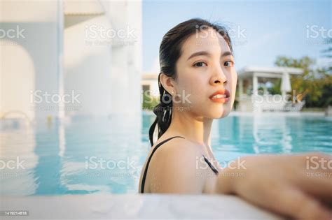 아름다운 여성의 초상화는 수영장에서 카메라를 바라보고 열대 스파에서 여름 방학에 카메라를 보면서 휴식을 취하며 얼굴에 선 스크린 로션을 쏟아 붓습니다 건강한 생활방식에 대한