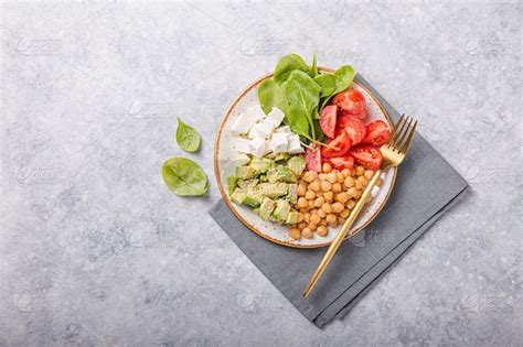 佛碗配牛油果鹰嘴豆羊乳酪新鲜菠菜西红柿和一杯水健康素食排毒平衡膳食概念前视图副本的空间