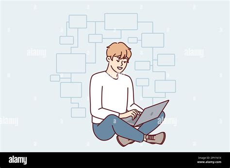 Young Man Programmer Sits Cross Legged On Floor With Laptop On Lap And