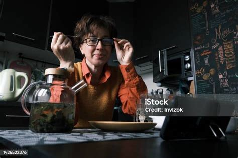 여자는 부엌에 앉아서 뜨거운 차를 마시고 수제 매실 케이크를 먹고 스마트 폰을 사용하고 있습니다 가정 생활에 대한 스톡 사진 및 기타 이미지 Istock