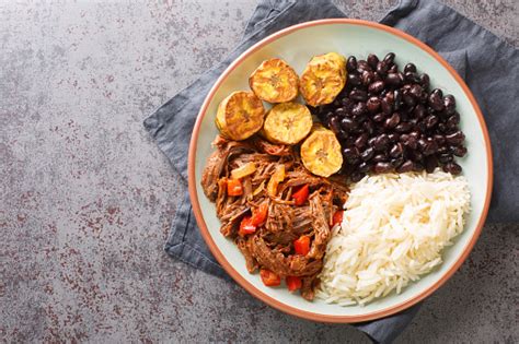 파베욘 크리올로 베네수엘라의 국가 요리는 갈가리 찢긴 쇠고기 쌀 검은 콩 튀긴 질경이를 접시에 근접 촬영합니다 수평 평면도