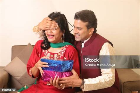 행복한 인도 남자는 사리에서 인도인 아내를 위해 깜짝 선물을 가져옵니다 둘 다 디왈리 축제에 인도 민족 의상을 입고 있습니다 2