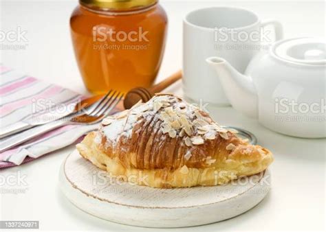 구운 바삭한 크루아상은 설탕 가루와 아몬드 플레이크를 나무 판에 뿌리고 흰색 세라믹 양조장과 흰색 테이블에 컵을 뿌립니다 조반 0명에 대한 스톡 사진 및 기타 이미지