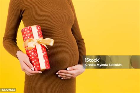 노란 배경에 선물 상자를 들고 갈색 드레스를 입은 임산부의 초상화를 닫습니다 임신 축하 복사 공간 가족에 대한 스톡 사진 및 기타 이미지 Istock