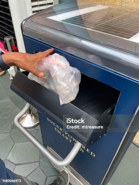 태양열 스마트 폐기물 압축기의 클로즈업 이미지 길거리 쓰레기통에 비닐 봉지를 넣는 알아볼 수 없는 사람 풋 페달 열기 호퍼 높은 시야 전경에 초점 거리에 대한 스톡 사진 및