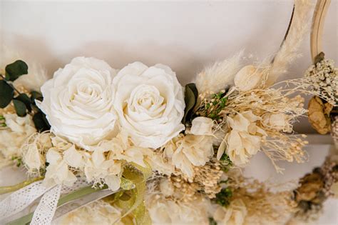 흰색 배경에 우아하게 배열된 흰 장미와 말린 꽃이 아름답게 제작된 꽃 화환은 가정 장식에서 소박한 매력과 자연스러운 우아함의 본질을 포착합니다 0명에 대한 스톡 사진 및