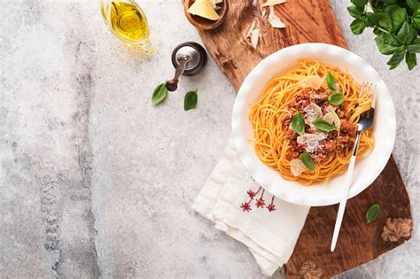파스타 스파게티 볼로냐세 회색 돌 또는 콘크리트 테이블 배경에 흰색 접시에 볼로냐 소스 토마토 소스 치즈 파르 메산 및 바질과 함께 이탈리아 스파게티를 맛있게 식욕을 돋우는