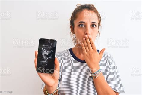 실수 두려움의 표정 침묵 비밀 개념에 무서워 손으로 고립 된 배경 커버 입에 깨진 스마트 폰을 들고 젊은 빨간 머리 여자 깨짐에