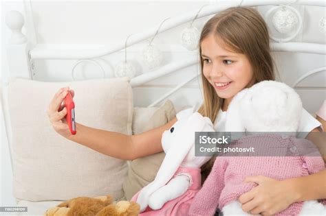 스마트 폰을 가진 소녀는 현대 기술을 사용합니다 좋아하는 장난감셀카 셀카 사진을 보내 친구 소셜 네트워크 아이는 장난감과 함께 셀카를 찍고 재미를 행복한 순간을 포착하십시오