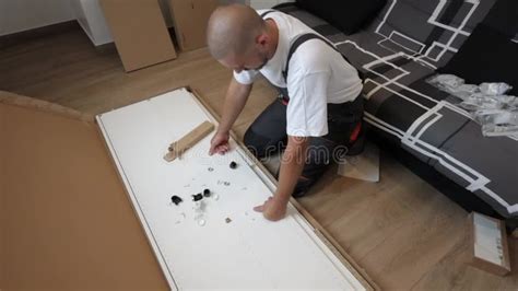 A Man Is Watching How To Assemble Furniture With His Own Hands A Male Craftsman In A Work Suit