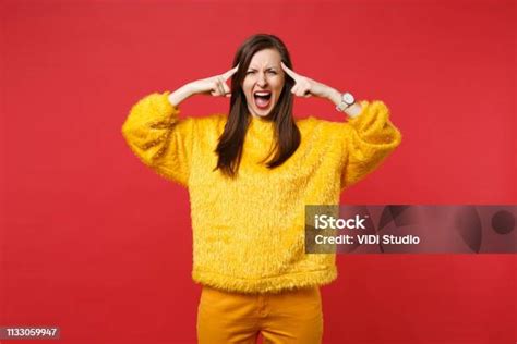성 난 비명의 초상화에 노란색 모피 스웨터는 사원에 손가락을 가리키는 스튜디오에서 붉은 벽 배경에 고립 된 머리 사람들은 진심으로 감정 라이프 스타일 개념입니다 복사 공간을