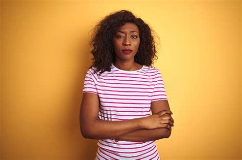 고립 된 노란색 배경 회의론자 및 긴장위에 줄무늬 티셔츠를 입은 젊은 아프리카 계 미국인 여성은 교차 된 팔로 얼굴에 표정을
