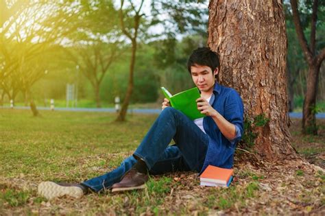 Joven Sentado Y Leyendo Un Libro En El Parque Foto Premium