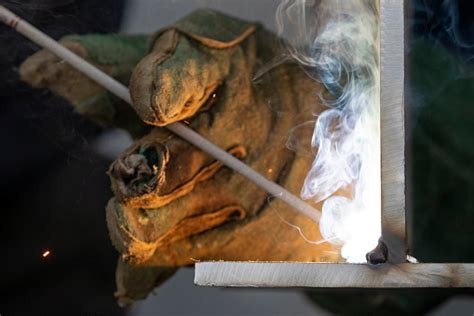 용접 연기의 보기를 닫습니다 용접공이 필렛 용접을 하고 있습니다 필렛 용접은 수직이든 각도이든 두 조각의 금속을 함께 결합하는 프로세스를 말합니다 강철에 대한 스톡 사진 및