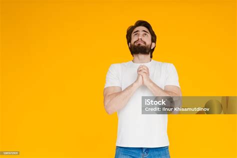 노란 벽 배경 스튜디오 초상화에 고립 된 포즈 흰색 캐주얼 티셔츠에 젊은 수염 남자 남자를 탄원 사람들은 라이프 스타일 개념을 감정 복사 공간을 모의합니다 손을 들고 기도로